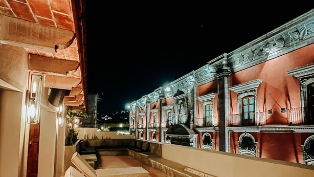 Terraço no telhado com cadeiras de descanso e vista para um edifício com arquitetura ornamentada.