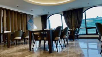 Uma área de jantar moderna com um candelabro, piso de mármore e vista da cidade.