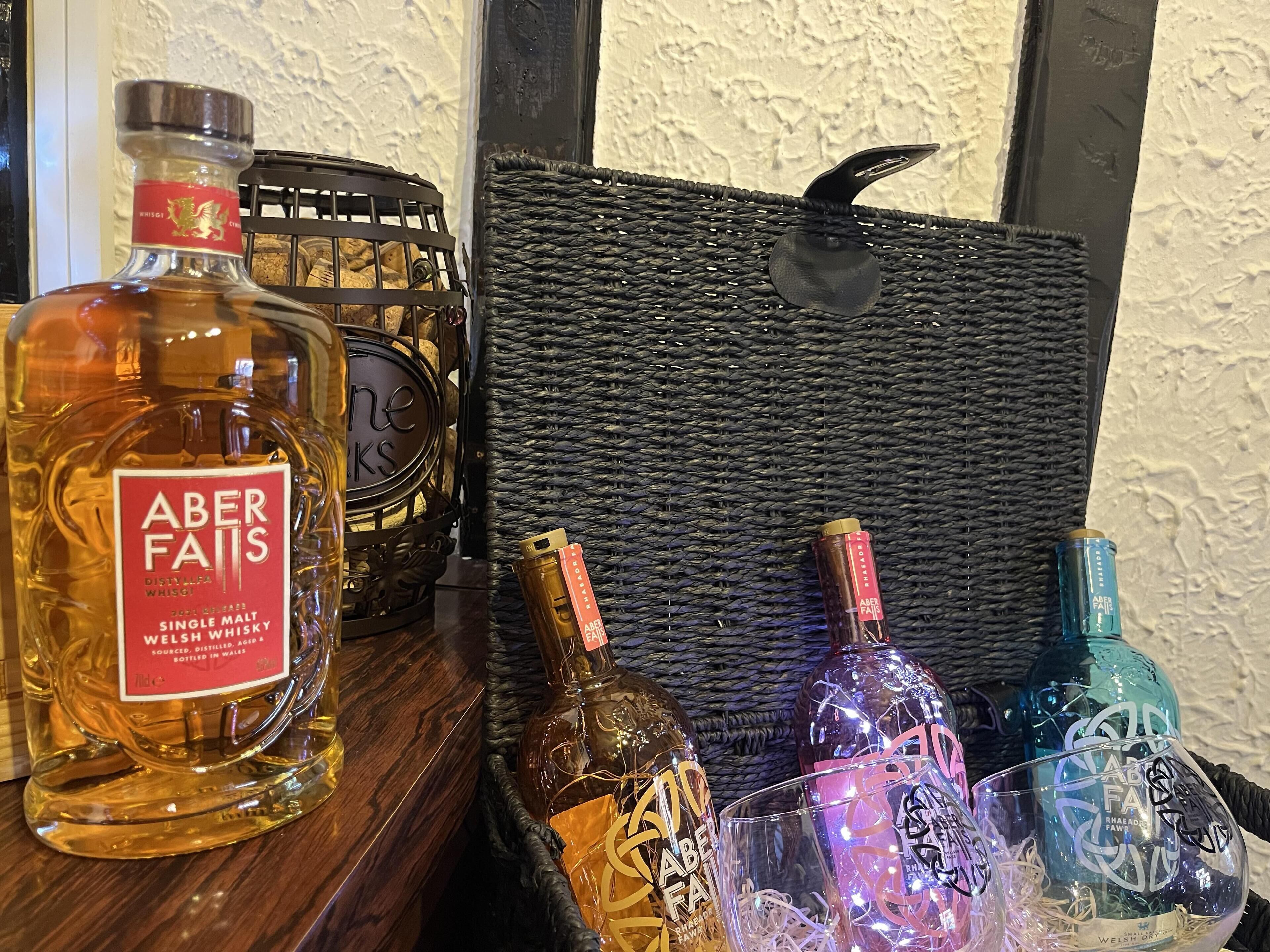 Uma garrafa de Whisky Single Malt Aber Falls, uma cesta de vime e uma gaiola de metal decorativa com uma placa.