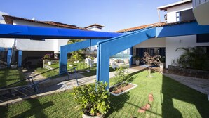 Um pátio com pérgola azul, plantas em vasos e telhado em azulejos.