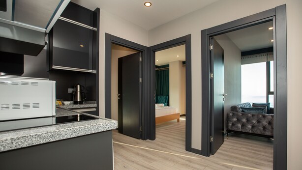 Quarto de hotel moderno com cozinha compacta, cama e área de estar.