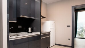 Cozinha moderna com armários escuros, pia de aço inoxidável e geladeira branca.