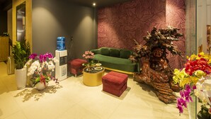 Uma sala de estar moderna com um sofá verde, pufes vermelhos, uma mesa de centro redonda e um grande dispensador de água.