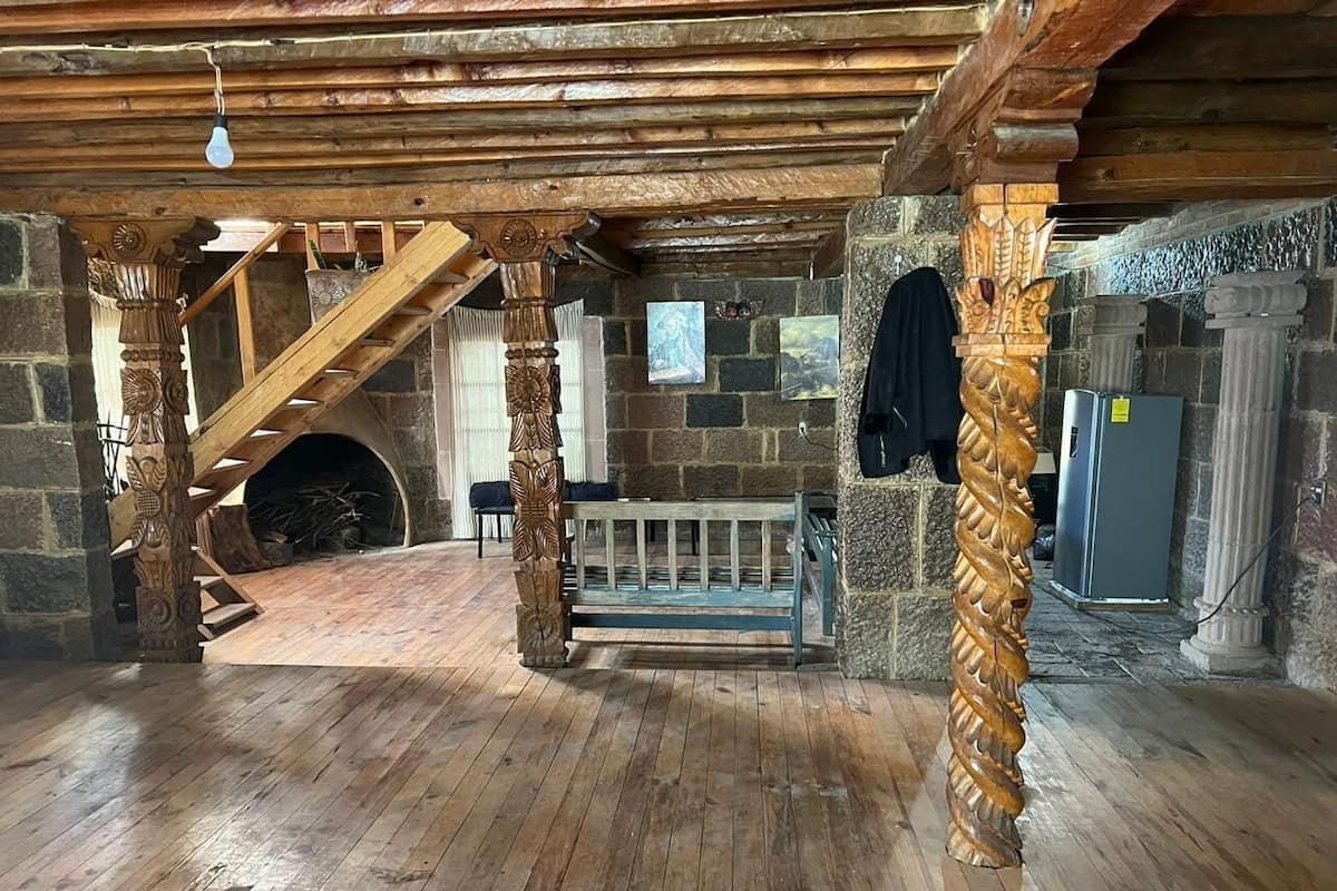 Um interior rústico com escada de madeira, paredes de pedra e lareira.