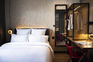 Quarto de hotel moderno com uma cama grande, uma escrivaninha com cadeira e um espelho.