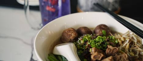Uma tigela de sopa com carne, legumes e macarrão.