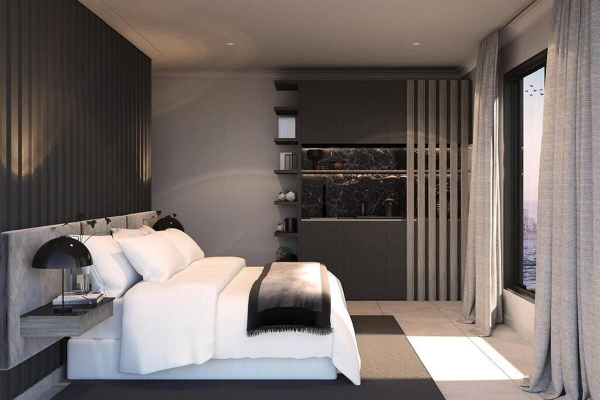 Quarto moderno com cama grande, mesas de cabeceira, estante embutida e vista para o exterior.