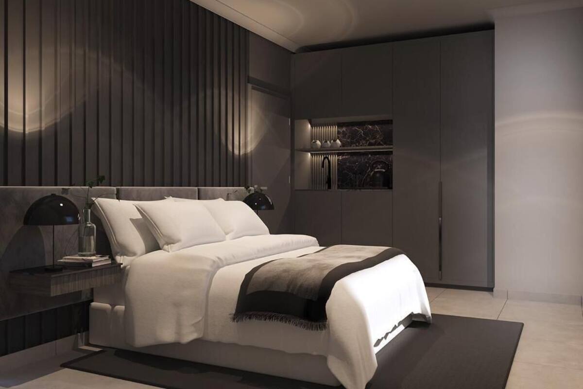 Quarto moderno com uma cama grande, mesas de cabeceira e prateleiras embutidas.