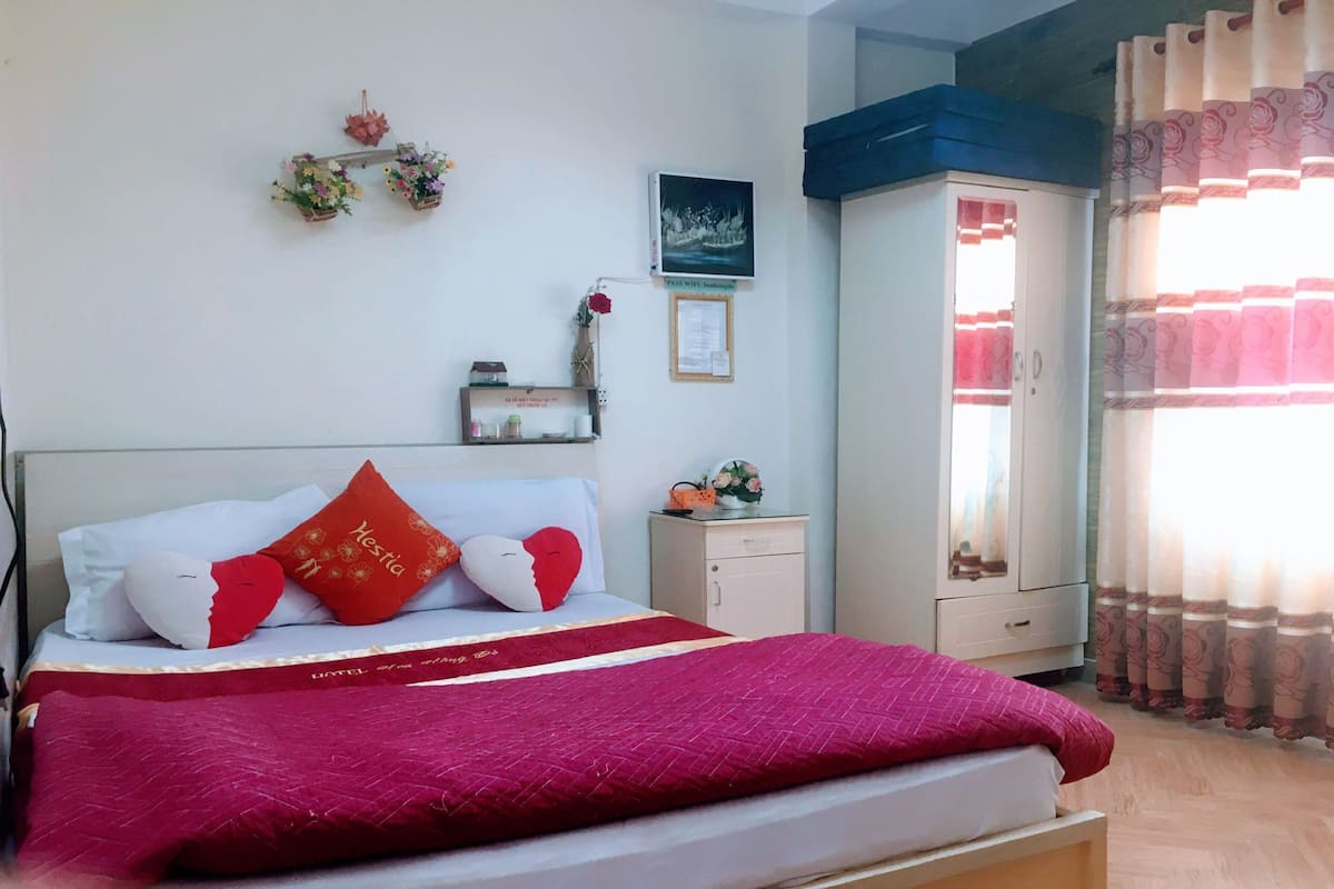 Quarto bem arrumado com cama, mesa de cabeceira, guarda-roupa e um quadro na parede.