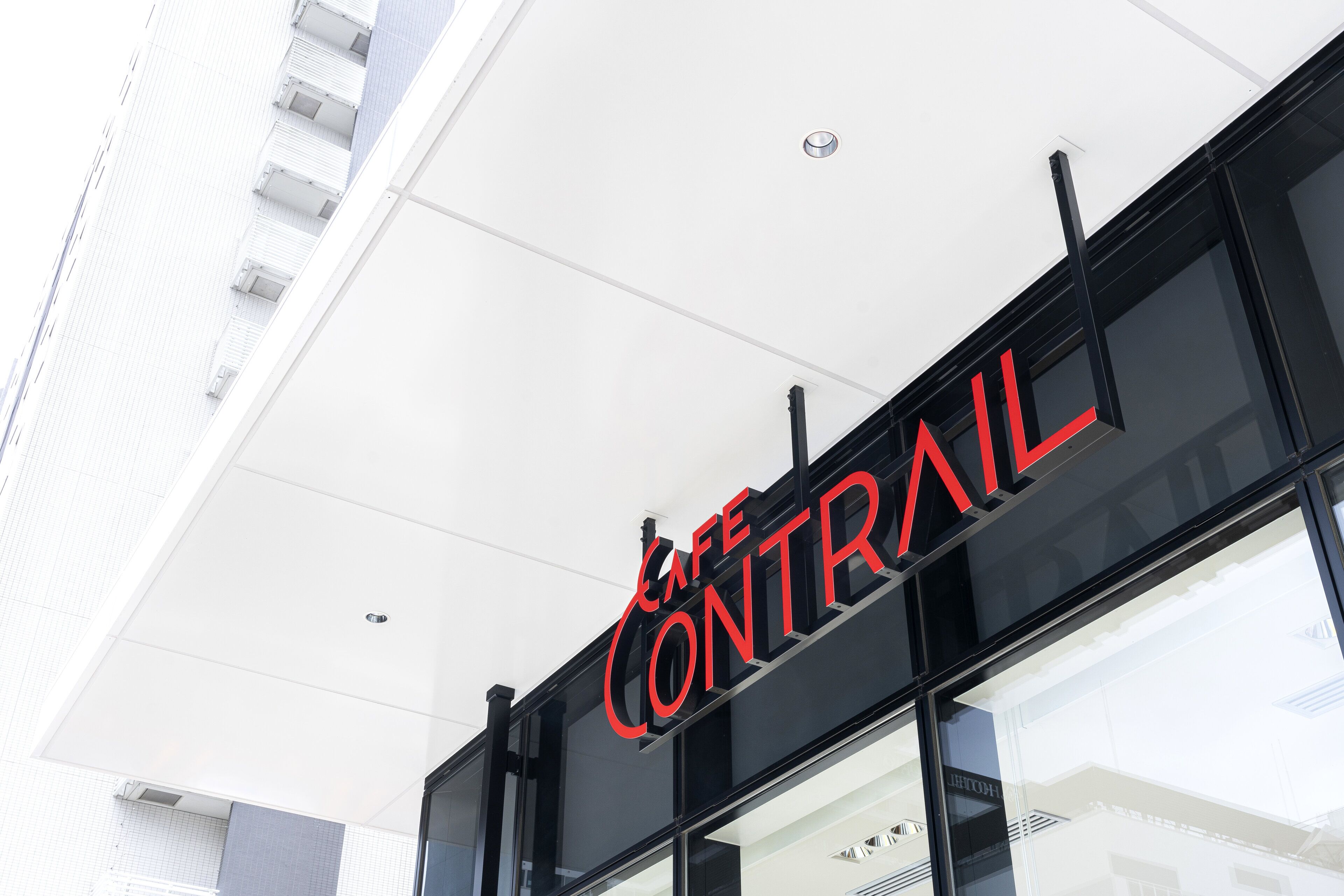 Um edifício com uma placa grande exibindo a inscrição 'Café Central' em letras vermelhas.