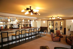 Uma área de bar com balcão, banquetas e um espaço de estar com cadeiras e um sofá.