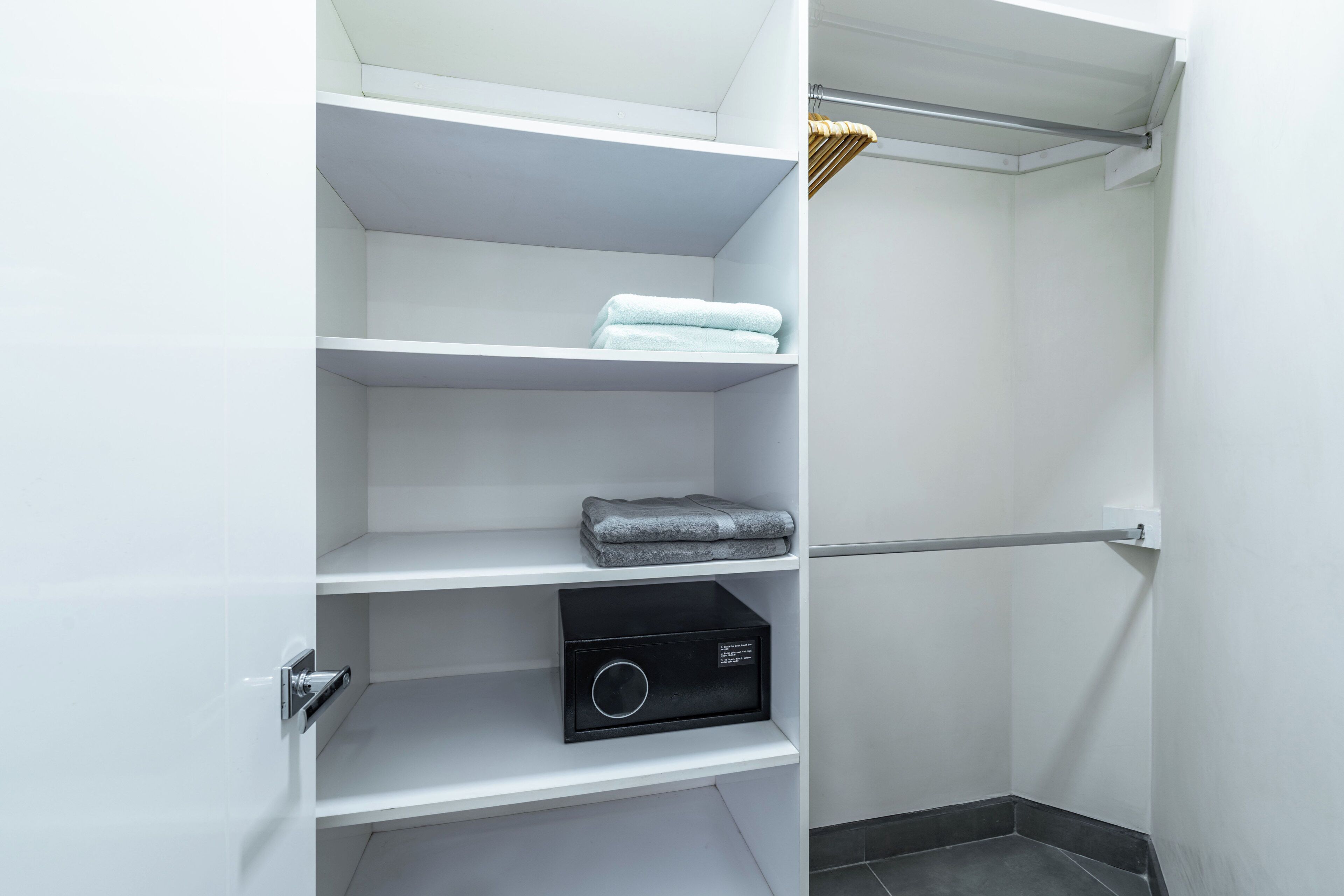 Um closet espaçoso com prateleiras brancas, uma barra para pendurar roupas e um eletrodoméstico preto na prateleira inferior.