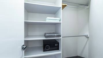 Um closet espaçoso com prateleiras brancas, uma barra para pendurar roupas e um eletrodoméstico preto na prateleira inferior.