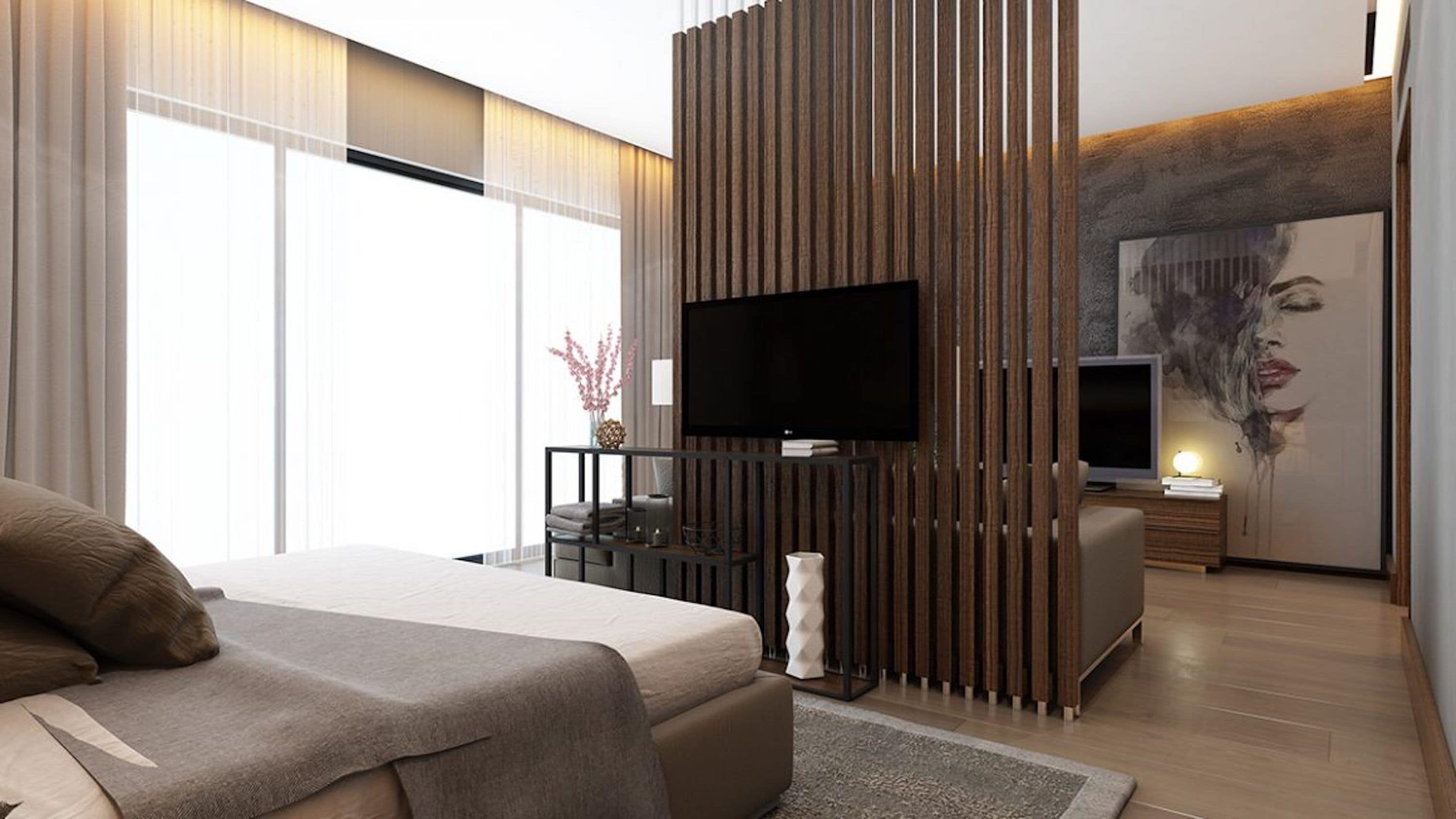 Um quarto moderno com uma cama grande, uma TV fixada em um painel de madeira, uma mesinha de cabeceira e um quadro na parede.
