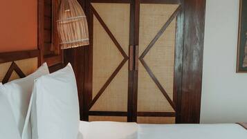 Quarto de hotel com cama, luminária de fibra natural e divisória de madeira com design geométrico.