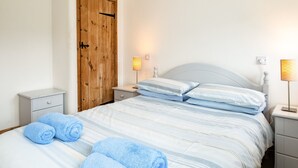 Quarto com cama, duas mesas de cabeceira, porta de madeira e luminária.