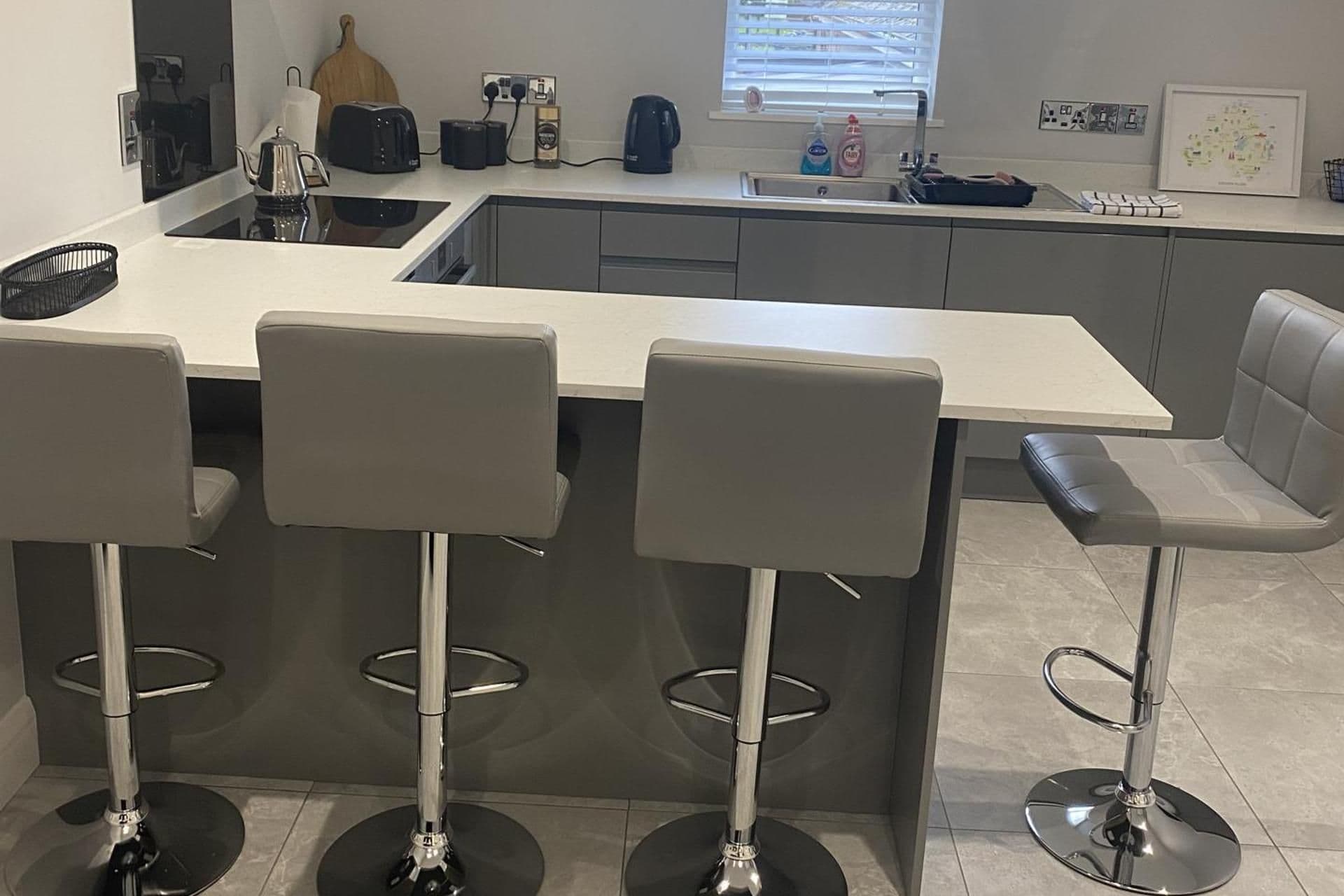 Cozinha moderna com ilha central, banquetas e pia embutida.