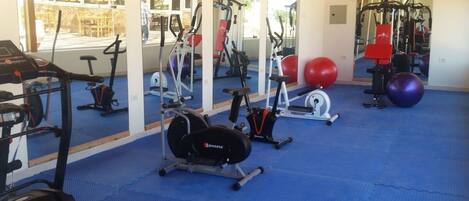 Uma academia com aparelhos de cardio, equipamentos de musculação e bolas de exercício.