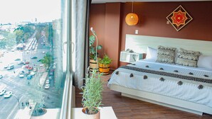 Quarto com uma cama grande, vista para uma rua da cidade e janela com vista para a rua.