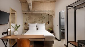 Quarto moderno com cama, mesa de cabeceira, cadeira e escrivaninha com abajur.