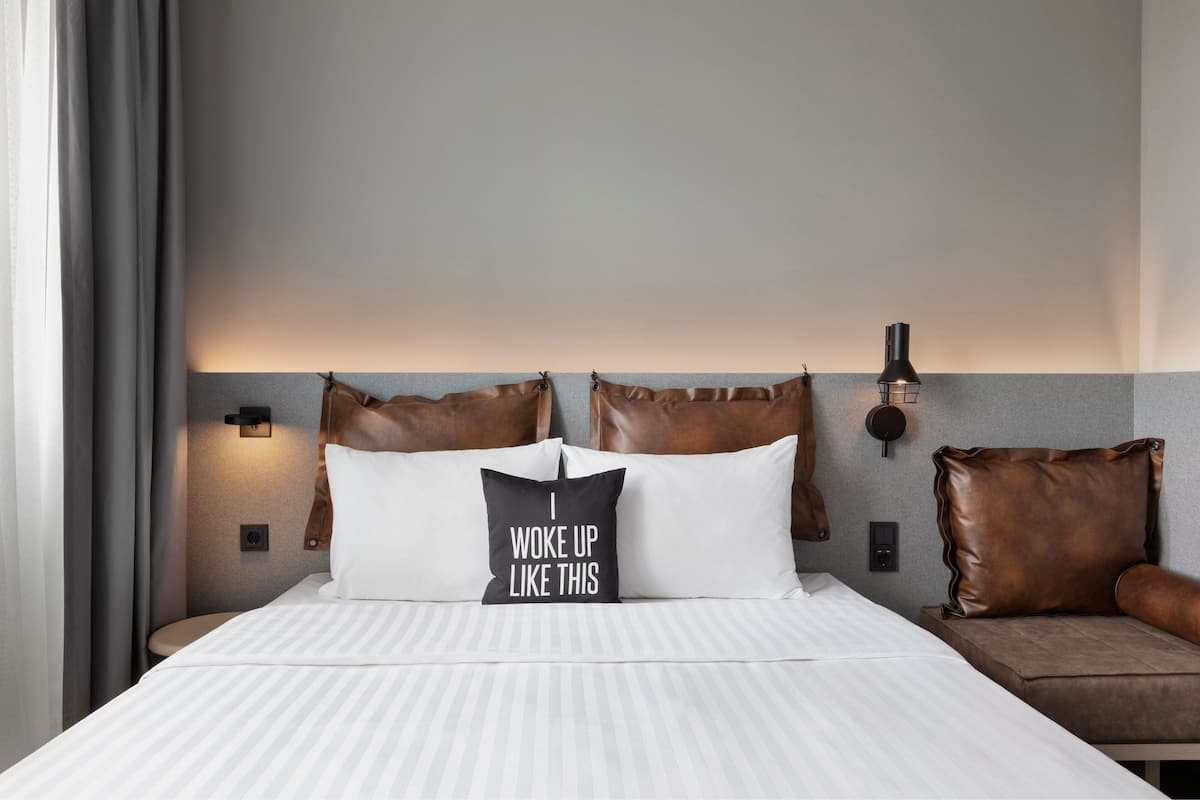Quarto de hotel com cama, sofá e luminária na parede.
