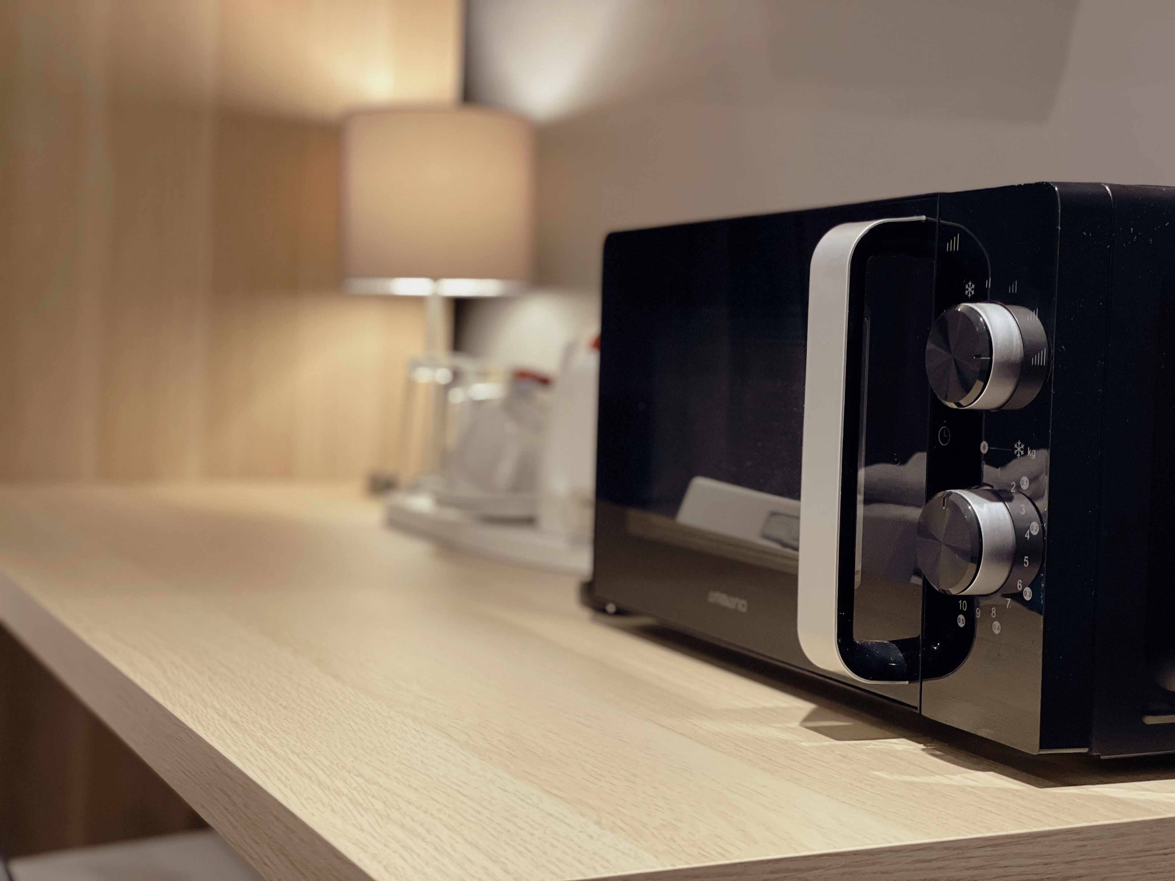 Uma cozinha moderna com micro-ondas embutido, máquina de café e bancada de madeira.