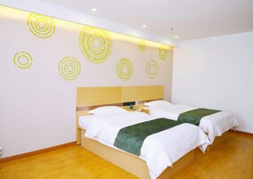 Quarto de hotel com duas camas, piso de madeira e adesivos circulares nas paredes.