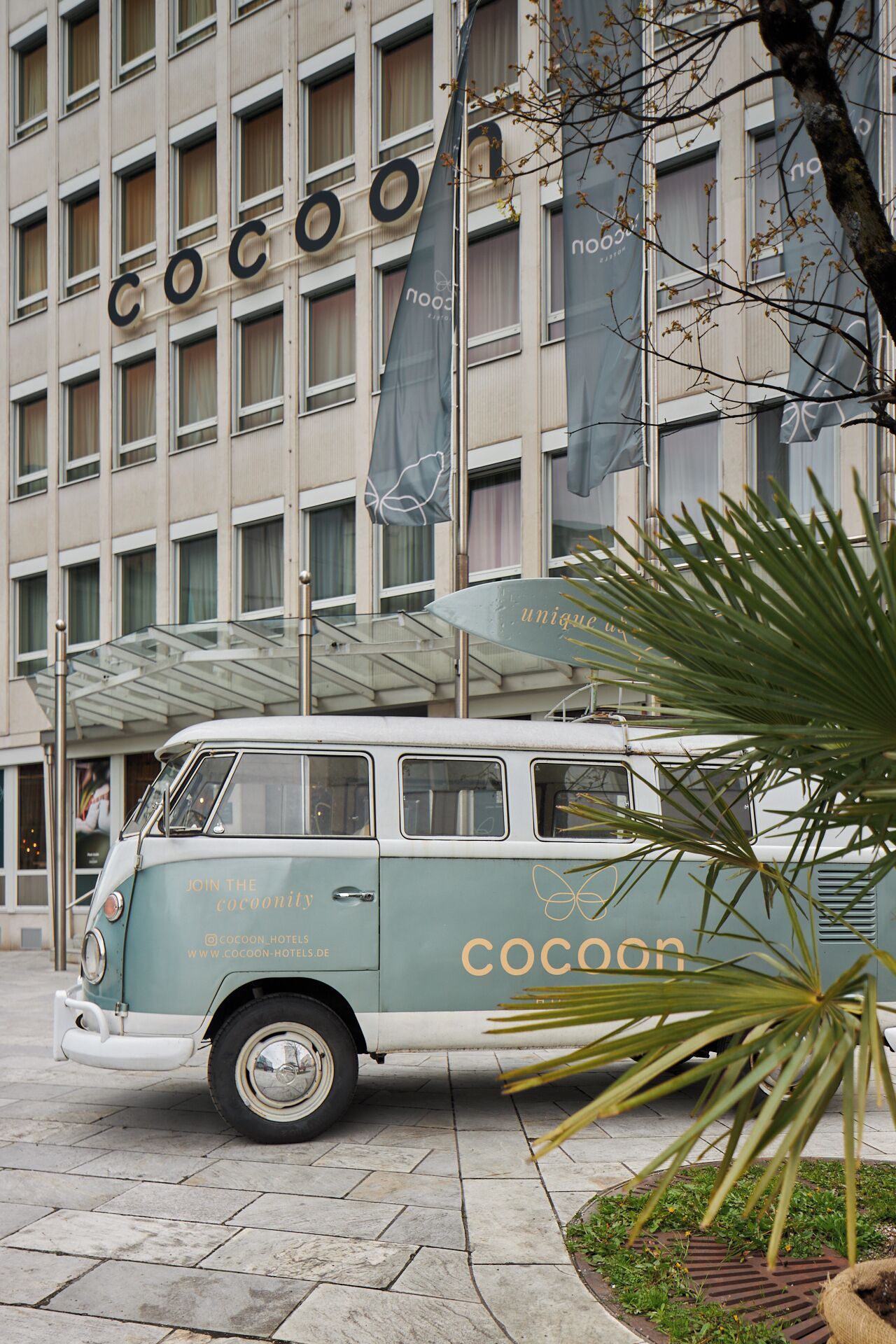 Uma carrinha antiga estacionada em frente a um edifício com a placa 'cocoon'.