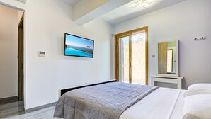 Quarto com cama, televisão na parede, janela com vista e mesa de cabeceira com espelho.