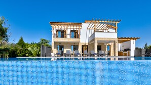 Uma casa moderna de dois andares com piscina em frente.