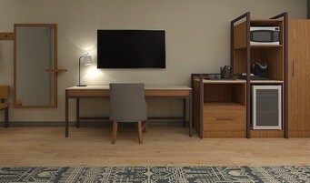 Quarto compacto com escrivaninha, cadeira e prateleira para micro-ondas embutida.