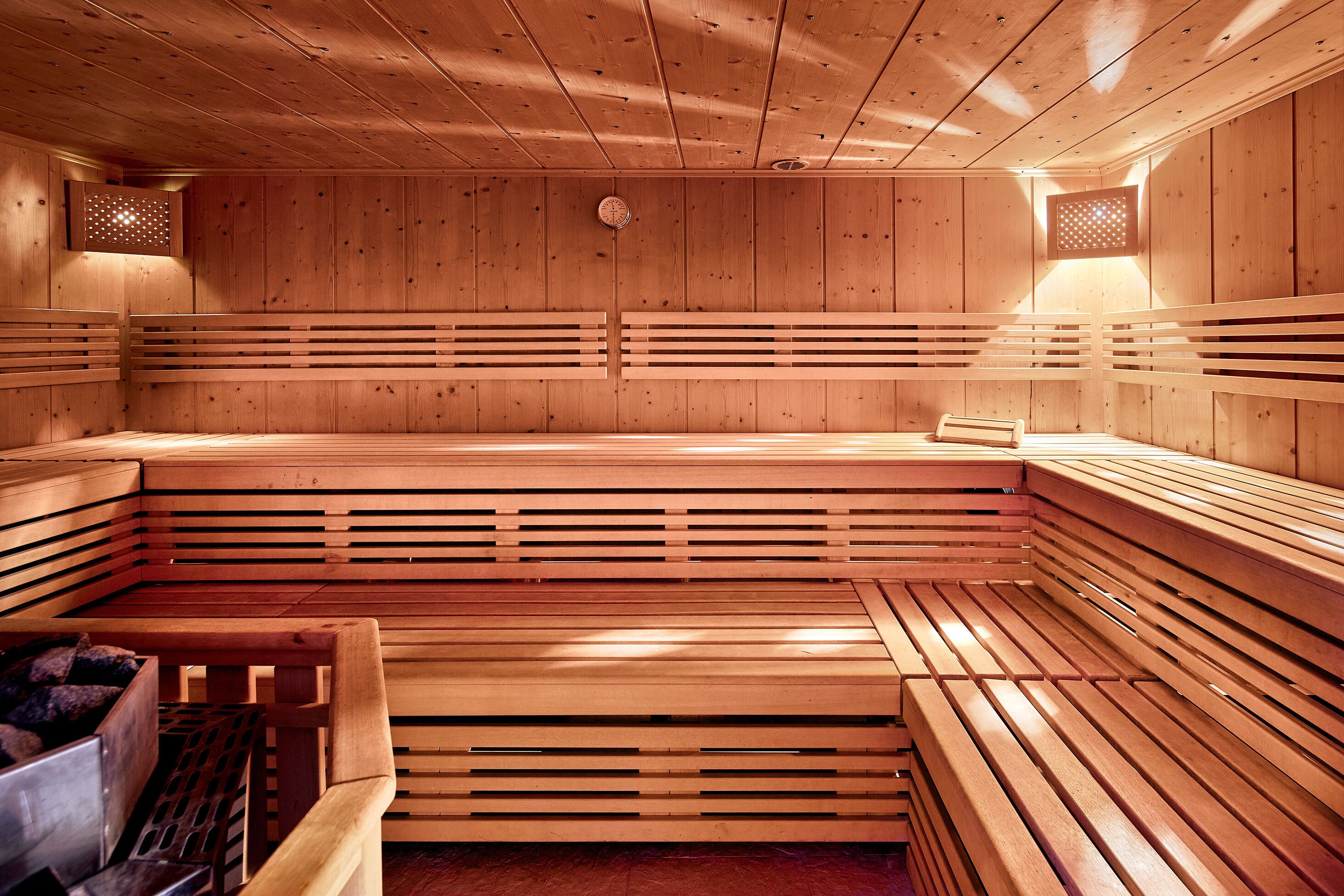 Uma sauna com bancos e assentos de madeira, paredes e teto de madeira.