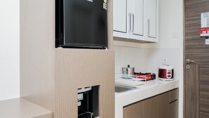 Uma cozinha compacta com geladeira embutida, cafeteira e chaleira na bancada.