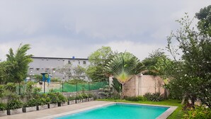 Piscina retangular com borda revestida em azulejo, rodeada por um gramado bem cuidado e diversas plantas.