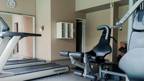 Uma academia com esteira, banco de musculação e diversos equipamentos de exercício.