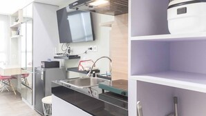 Cozinha moderna com pia de aço inoxidável, forno embutido e televisão de tela plana fixada acima do balcão.