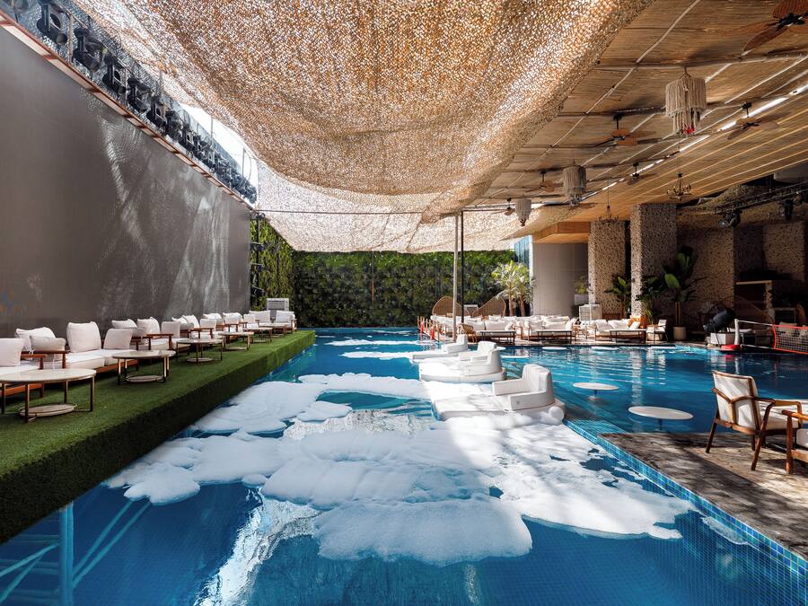 Uma área de piscina com gelo artificial, espreguiçadeiras e um teto com luminárias pendentes.