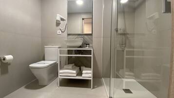 Uma casa de banho moderna com sanita, lavatório e cabine de duche em vidro.