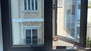 Janela com vista para um edifício com várias janelas e uma varanda.