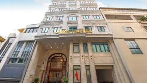 Entrada de hotel com fachada imponente, uma bandeira vermelha e escadaria que leva à entrada.