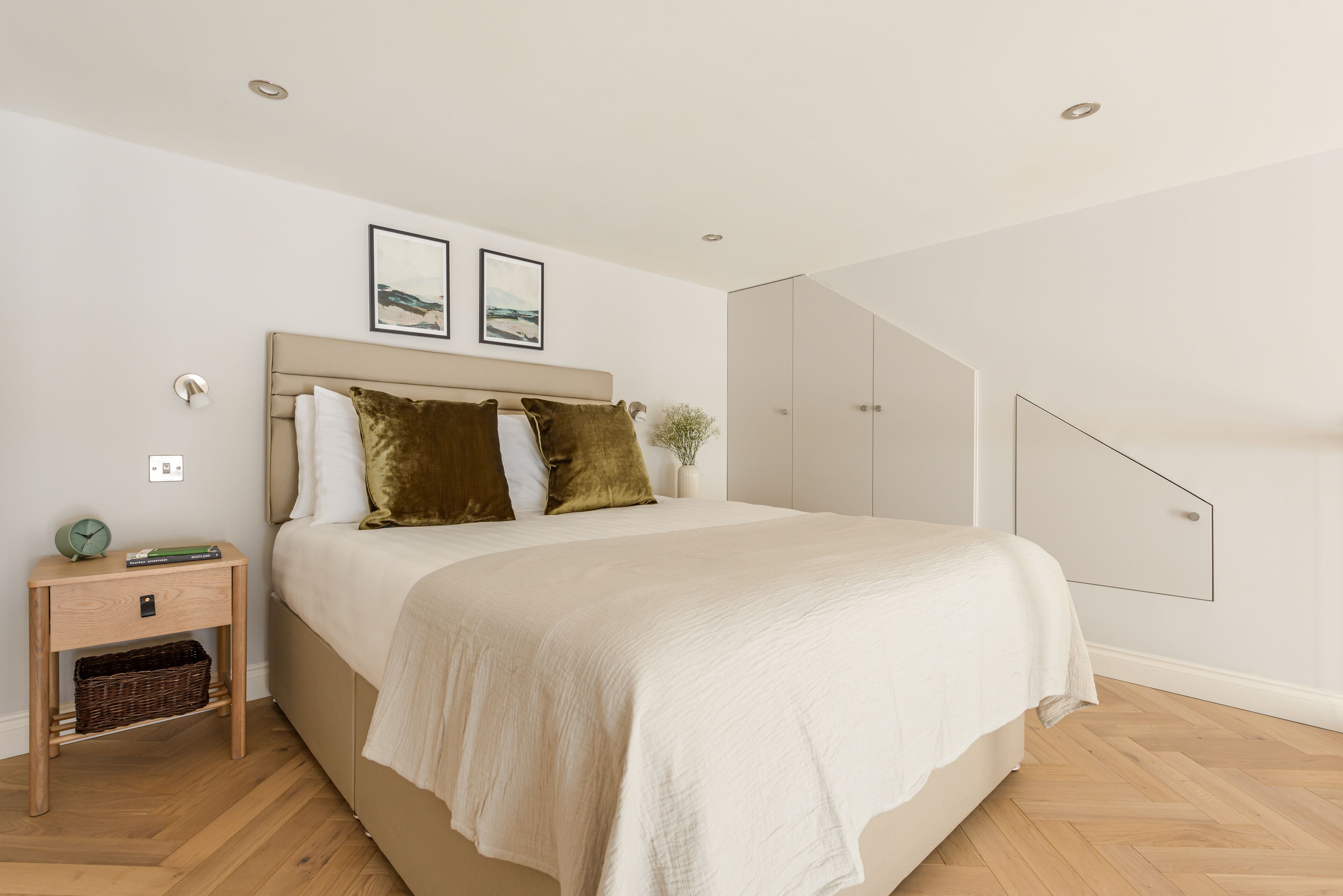 Quarto com cama, mesa de cabeceira e guarda-roupa fixo na parede.