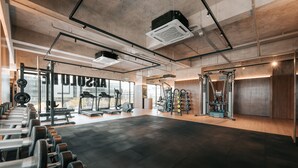 Uma academia espaçosa com diversos equipamentos de exercício, amplas janelas e um design moderno e limpo.
