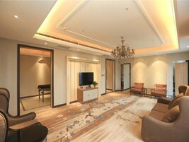 Uma sala de estar espaçosa com uma televisão grande, um candelabro e um tapete estampado.