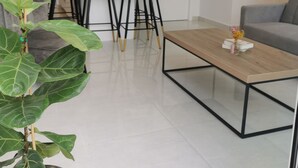 Uma sala de estar moderna com uma mesa de centro de madeira, um sofá cinza e uma área de jantar com três cadeiras.