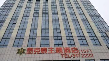 Um edifício alto com uma placa indicando um hotel chamado 'Xianglu Taihu Hotel', com um número de contato.