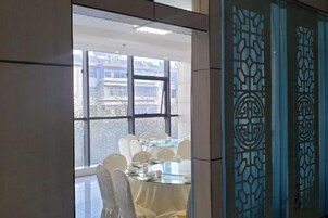 Sala de conferência com uma mesa redonda, cadeiras brancas e vista pela janela.