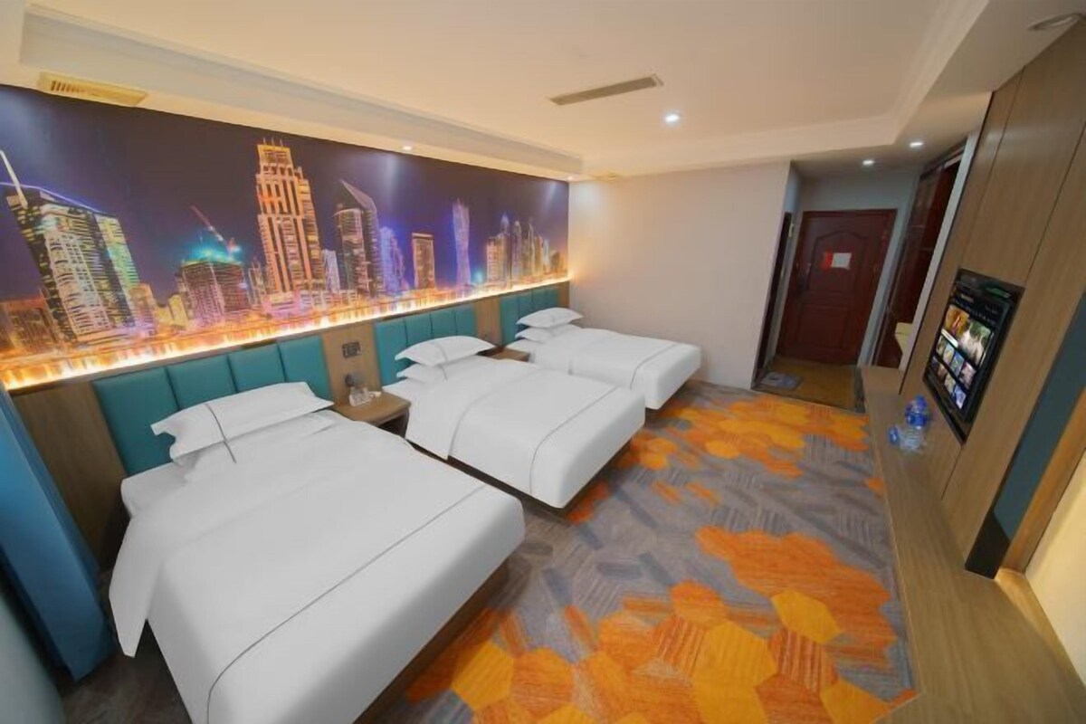 Quarto de hotel com duas camas, um mural da paisagem urbana e uma tela digital na parede.