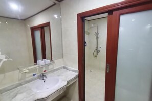 Casa de banho com lavatório de mármore, cabine de duche em vidro e porta com estrutura vermelha.