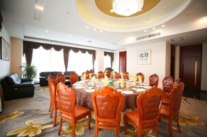 Sala de conferência com uma mesa redonda, cadeiras estofadas em laranja e piso coberto de carpete.
