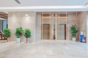 Um lobby moderno com piso de mármore, balcão de recepção e plantas em vasos.